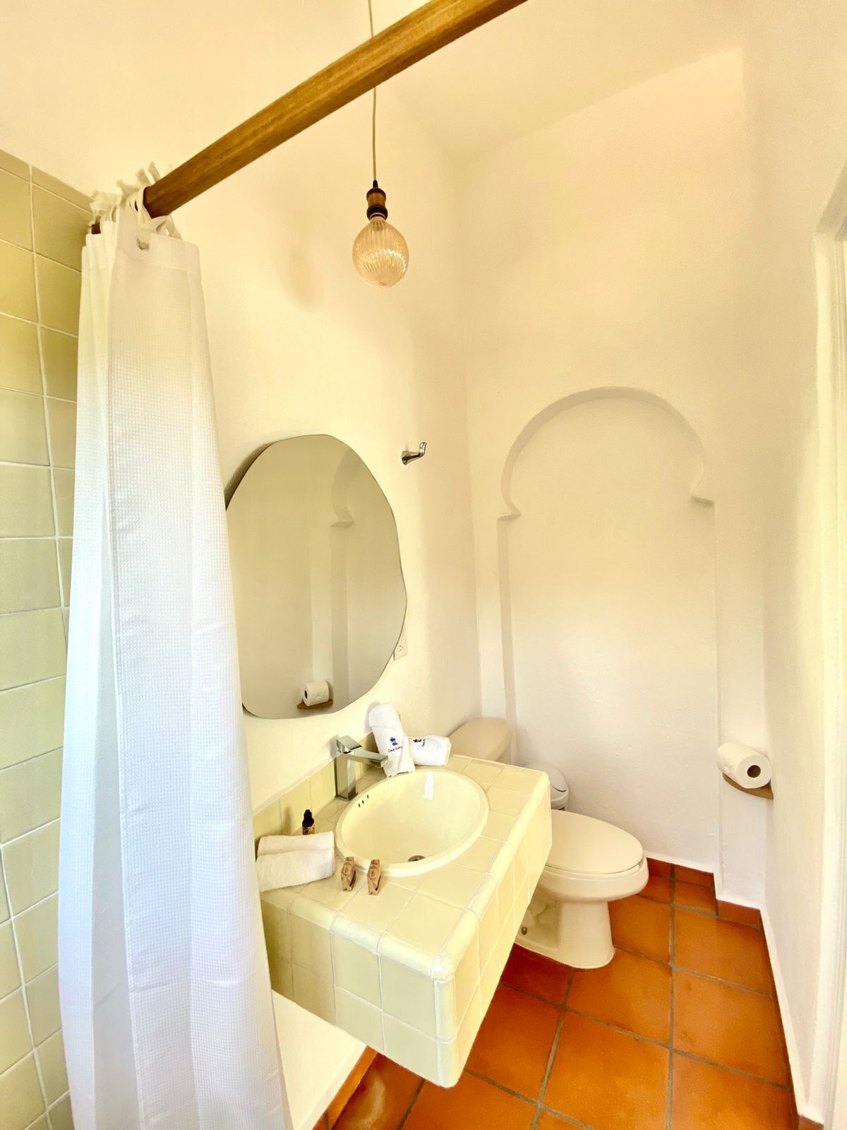 Casa de banho com uma pia branca, espelho e sanita.