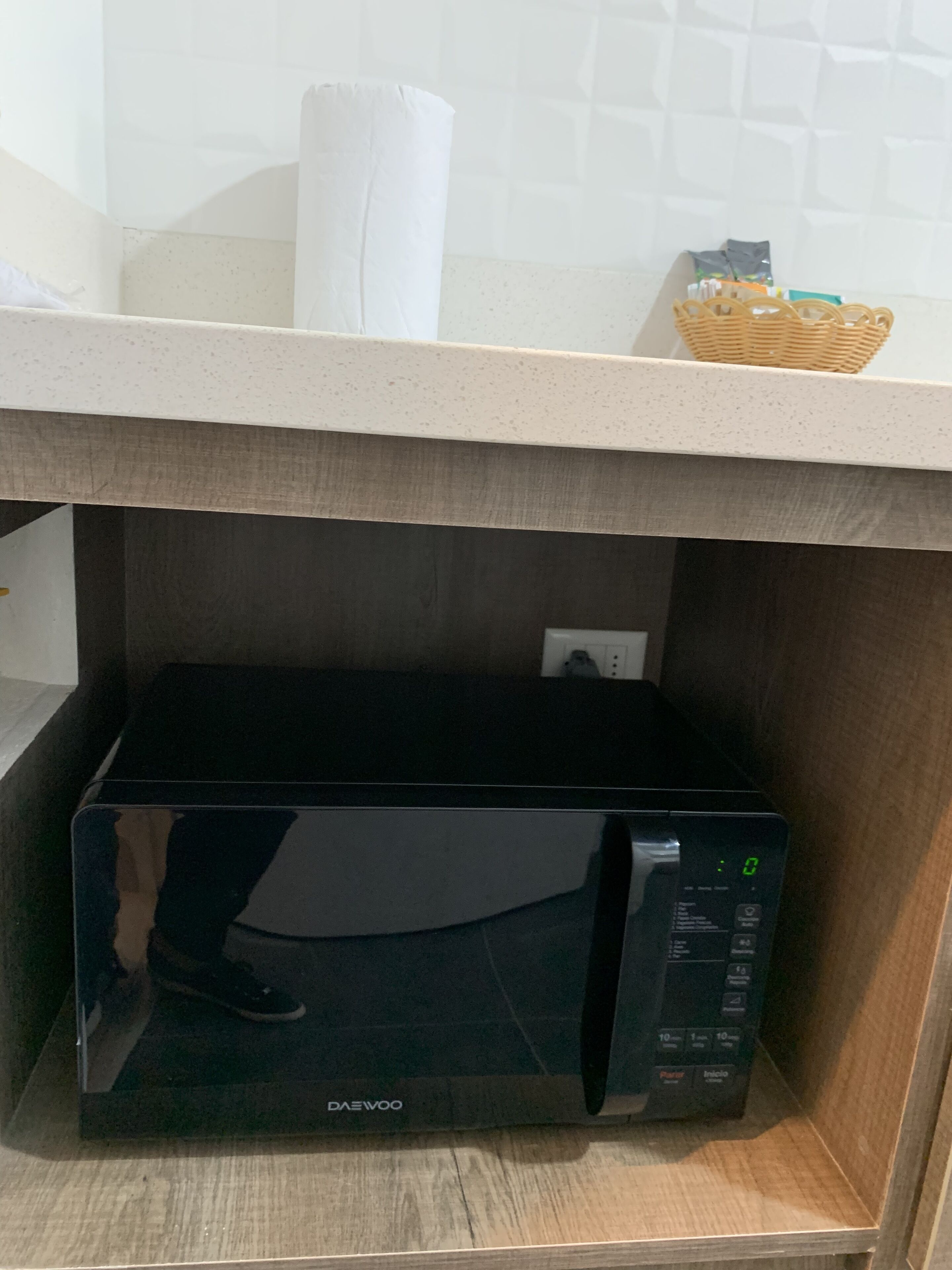 Forno de micro-ondas preto colocado sob a bancada da cozinha.