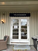 Entrada de hotel com uma placa que diz 'VELKOMMEN' e um letreiro de boas-vindas.