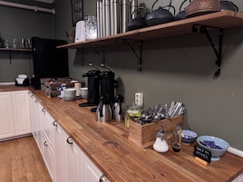 Uma bancada de cozinha com vários utensílios, uma cafeteira e um saleiro e pimenteiro.