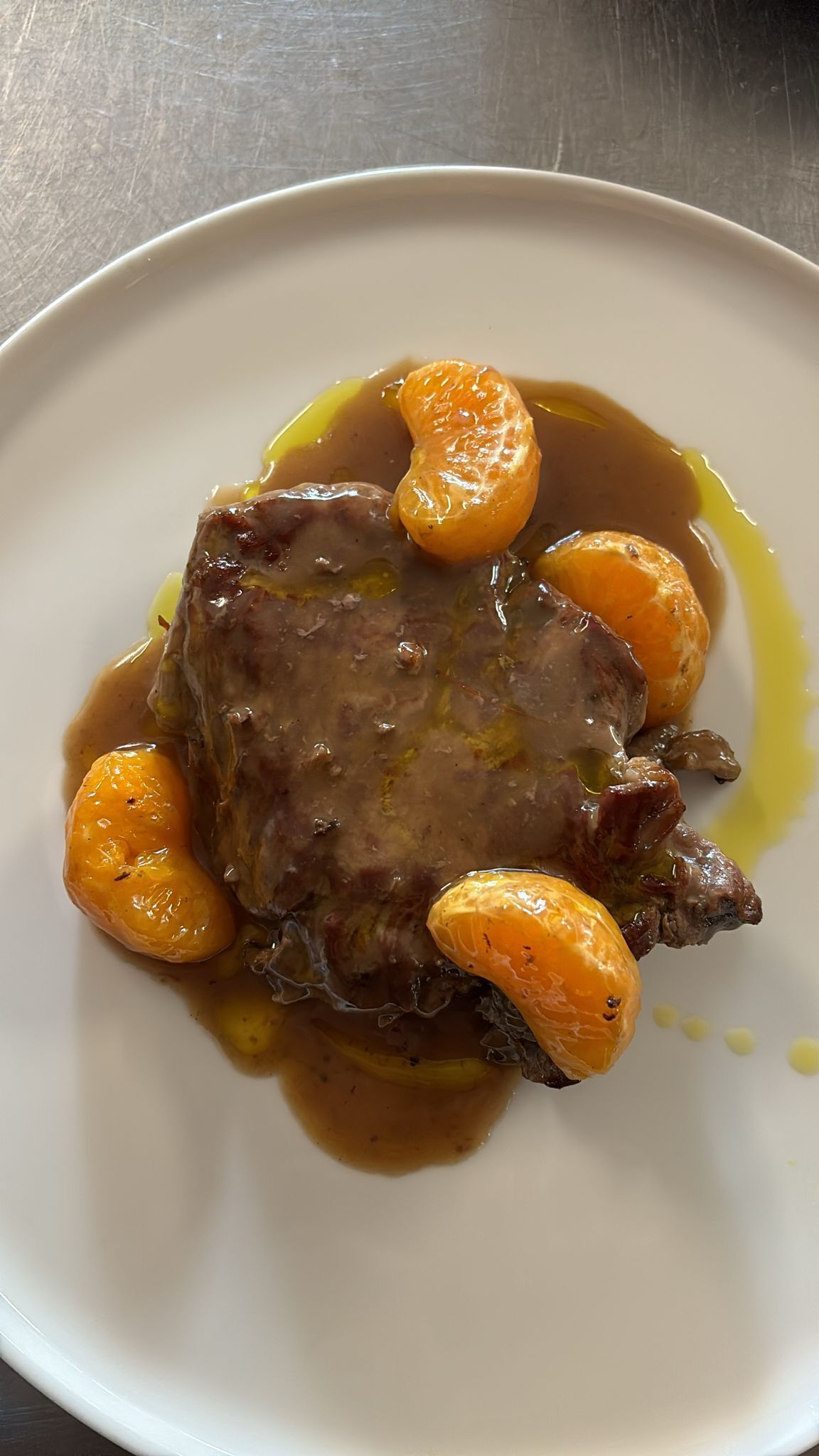 Um prato com bife, batatas assadas e molho marrom.