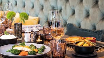 Mesa de jantar posta com pratos de comida, copos e velas, sugerindo um ambiente de restaurante.