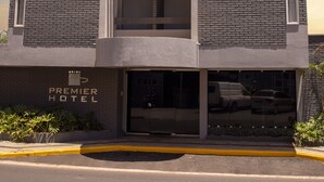 Um hotel com vários andares, fachada de tijolos, varandas e uma placa com a inscrição 'Premier Hotel'.