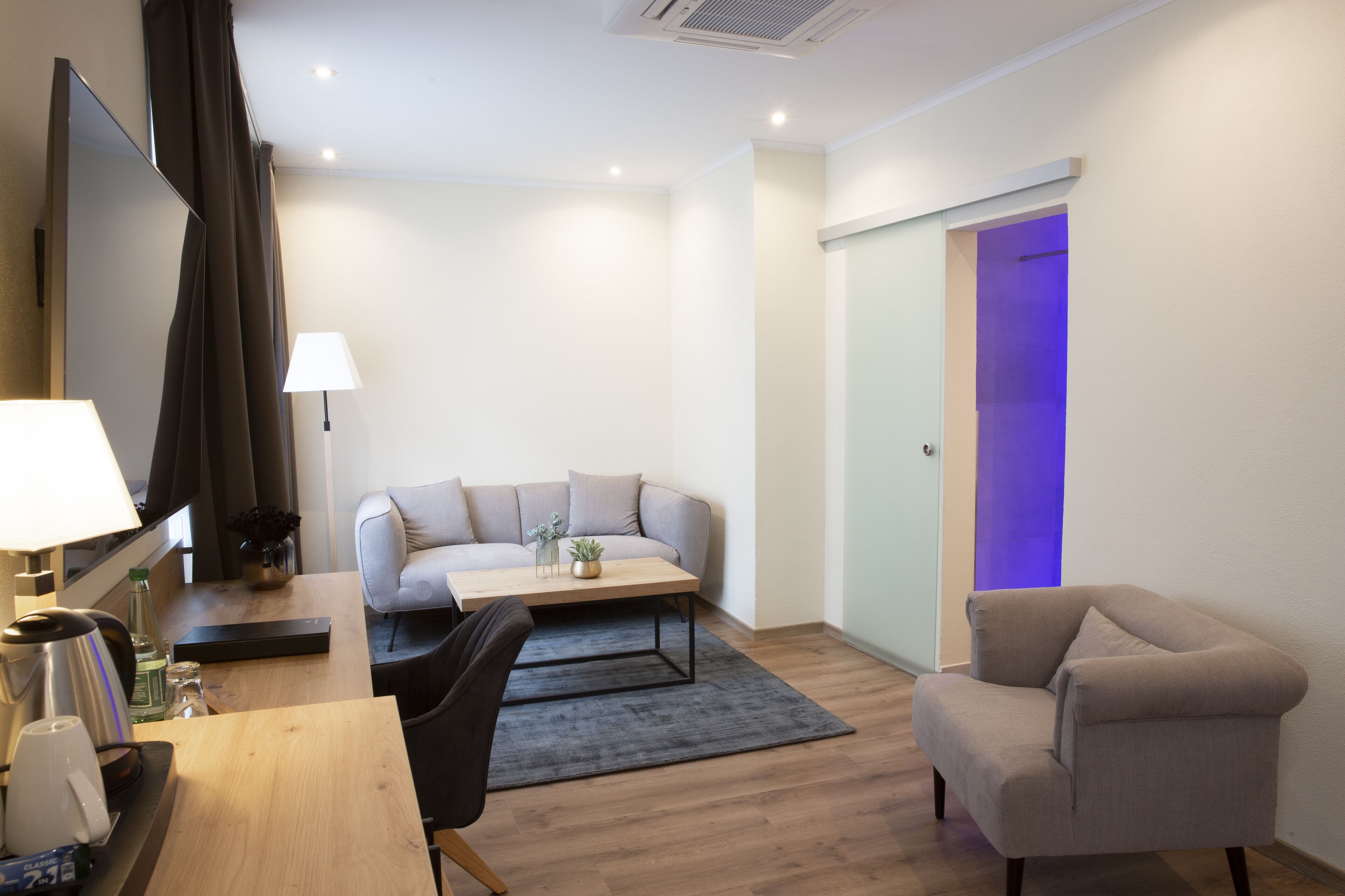 Uma sala de estar moderna com sofá, poltrona, mesa de centro e televisão de tela plana.