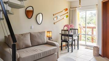 Uma sala de estar moderna com escada, ventilador de teto, sofá, mesa de centro e um espaço de jantar com cadeiras e mesa.