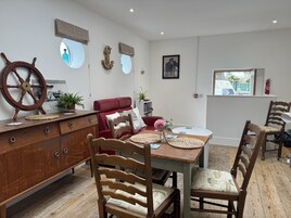 Uma sala de jantar com mesa de madeira, cadeiras e um sofá vermelho.