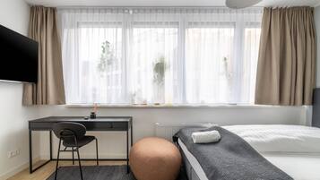 Quarto moderno com cama, escrivaninha e cadeira.