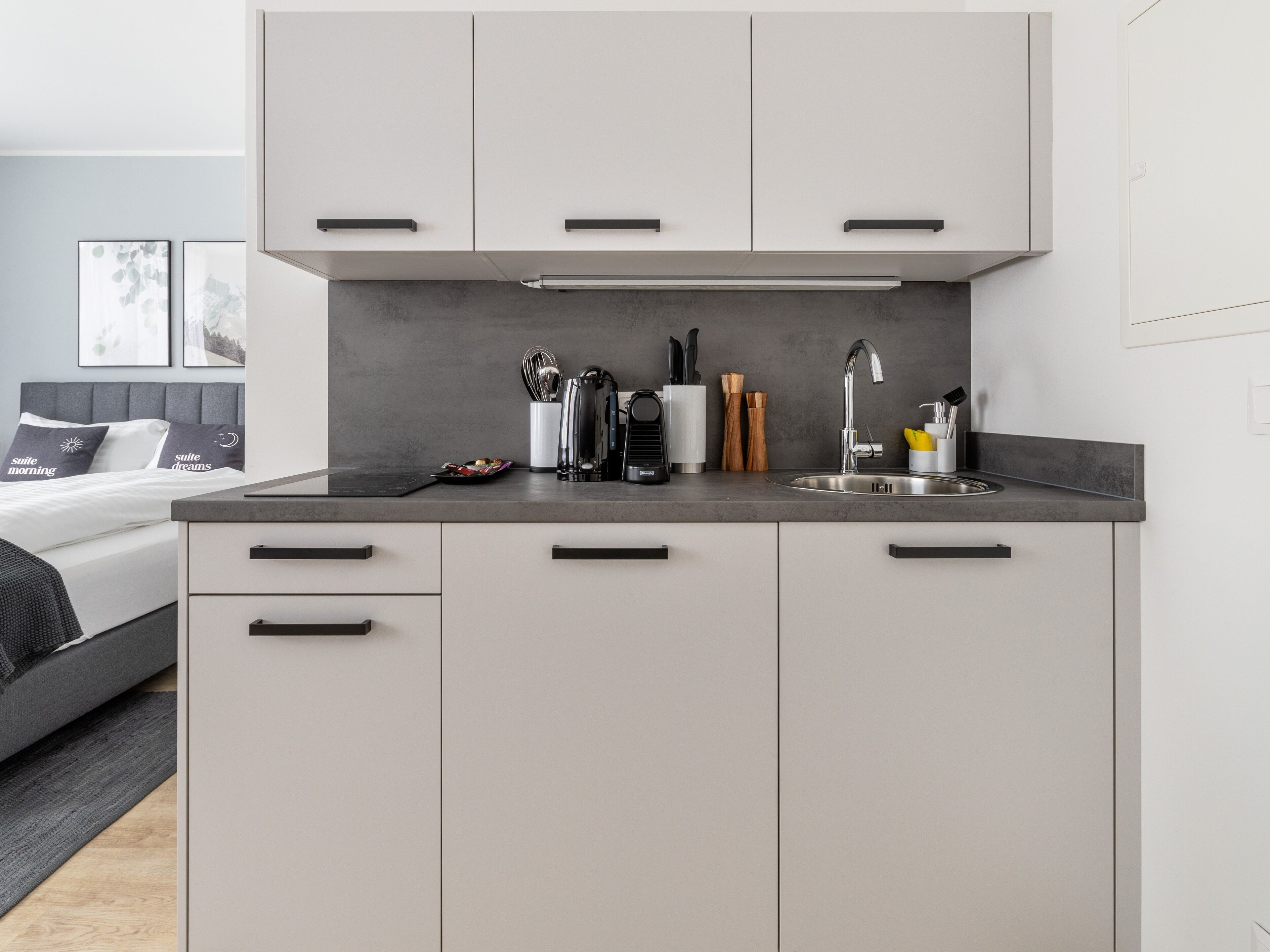 Uma cozinha compacta com design moderno, equipada com forno embutido, pia e cafeteira.