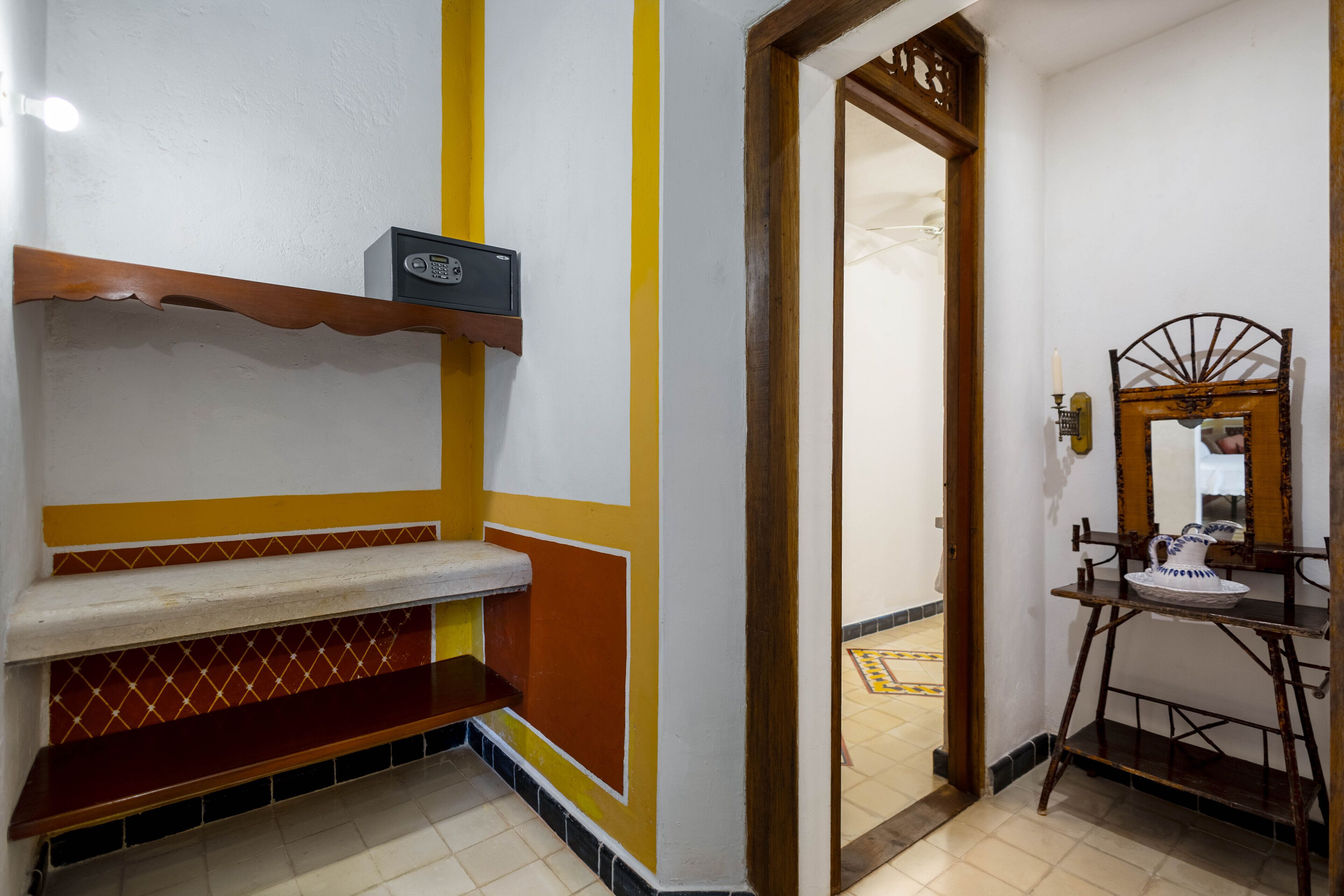 Casa de banho com toucador de madeira, espelho e prateleira com um rádio.