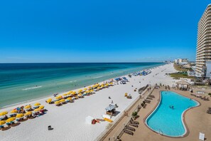 Um resort na praia com piscina, guarda-sóis e vista clara do oceano.