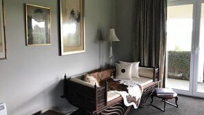 Um quarto com uma cama, mesa de cabeceira, luminária e janela com cortinas.