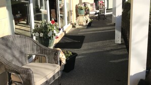 Uma área de varanda coberta com móveis de vime, plantas em vasos e luminária pendente.
