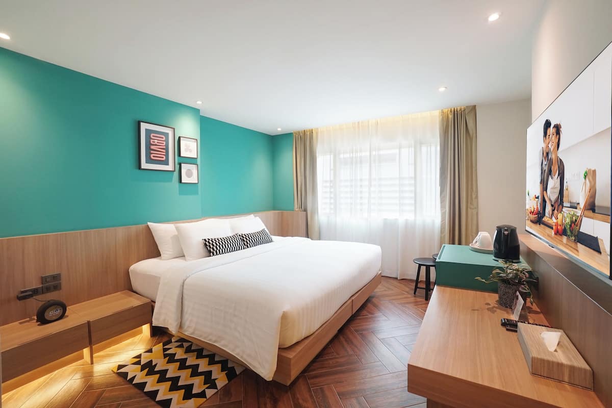 Quarto de hotel moderno com uma cama grande, uma escrivaninha e vista para a cidade.