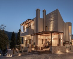 Uma casa moderna de dois andares com varanda, degraus de pedra e área de estar externa.