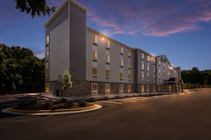 Um hotel de vários andares com design moderno, apresentando uma fachada em pedra e madeira, múltiplos acessos e estacionamento.