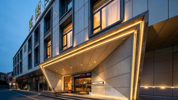 Entrada moderna de hotel com fachada geométrica e acesso iluminado.