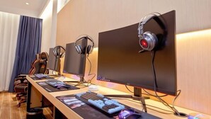 Uma sala de jogos com vários monitores, cadeiras gamer e uma mesa com teclado e mouse.