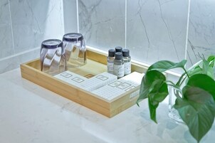 Uma bandeja de madeira com potes e garrafas de vidro, um teclado e uma planta em vaso sobre uma superfície com azulejos de mármore.