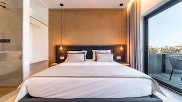 Um quarto moderno com uma cama grande, duas mesinhas de cabeceira e vista para o exterior através de uma grande janela.