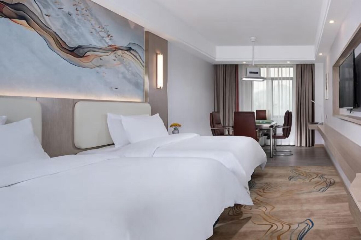 Quarto de hotel com uma cama grande, uma escrivaninha e uma televisão.