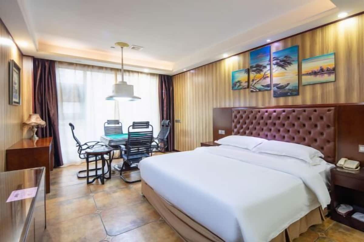 Quarto de hotel com cama, escrivaninha, cadeira, luminária e obra de arte na parede.