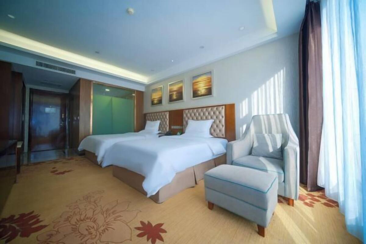 Quarto de hotel com uma cama grande, área de estar e vista para o exterior.