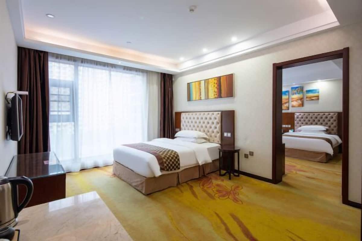Quarto de hotel moderno com uma cama grande, uma escrivaninha e vista para a cidade.