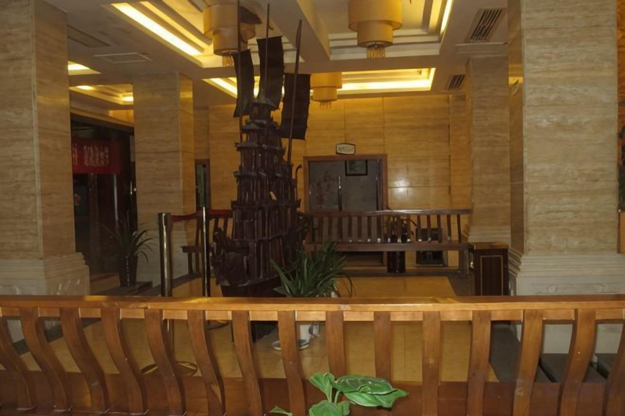 Um saguão com balcão de recepção, escada e escultura metálica decorativa.