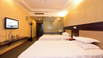 Quarto de hotel com duas camas, televisão, cabideiro e porta de banheiro.