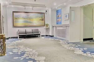 Uma área de recepção com uma pintura grande, um espaço de estar e um piso estampado.