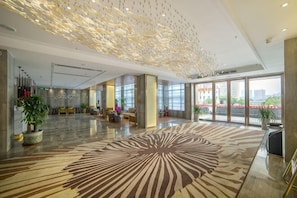 Um hall amplo com piso estampado, janelas grandes e design moderno no teto.