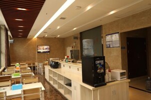 Um saguão de hotel com balcão de recepção, área de estar e máquina de café.