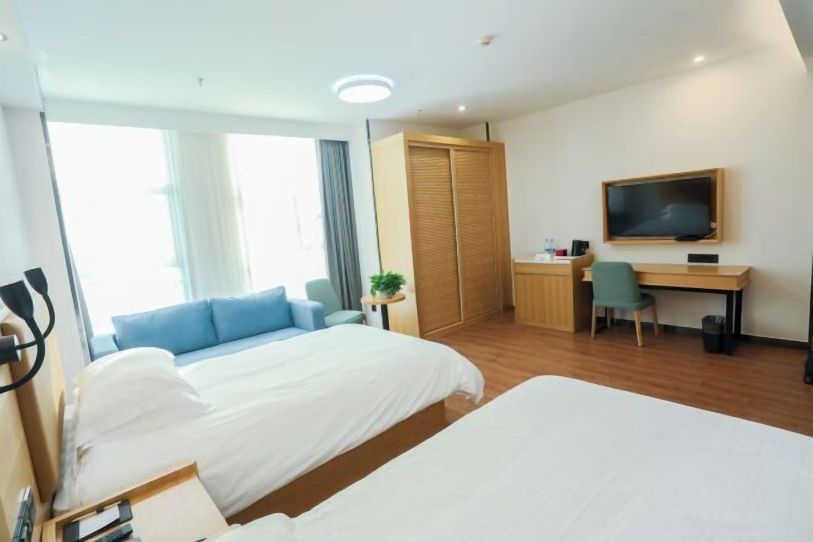Quarto de hotel com duas camas, uma escrivaninha, televisão e guarda-roupa.