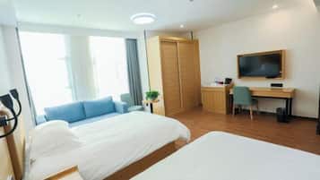 Quarto de hotel com duas camas, uma escrivaninha, televisão e guarda-roupa.