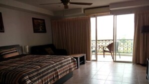 Quarto com cama, cadeira, televisão e varanda com vista.