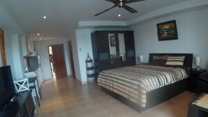Quarto com cama, escrivaninha e ventoinha no teto.