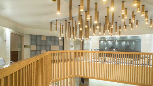 Um interior moderno com corrimão de madeira, luminárias pendentes e escada de vidro.