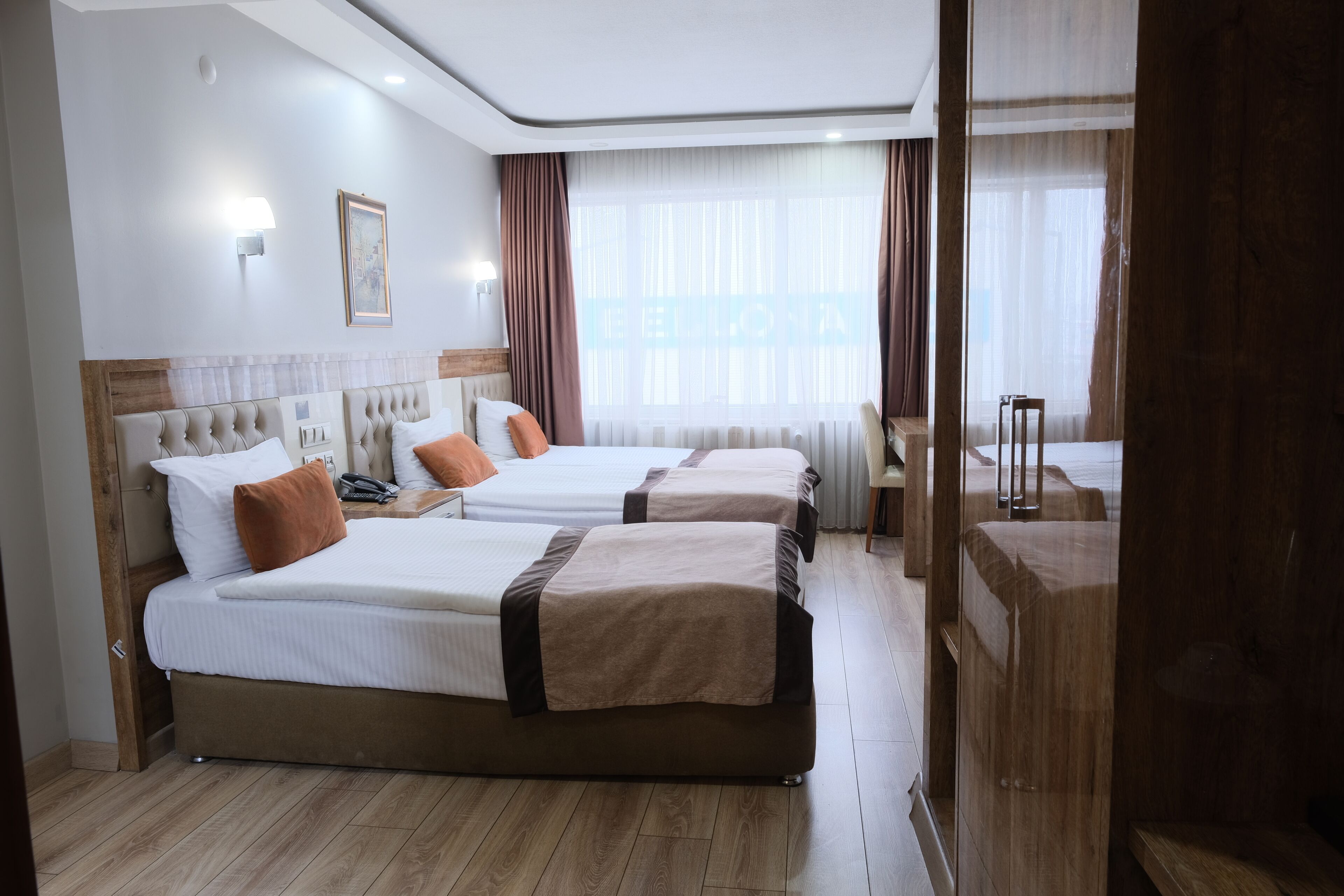 Quarto de hotel com duas camas, uma escrivaninha e uma cadeira.