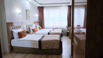 Quarto de hotel com duas camas, uma escrivaninha e uma cadeira.