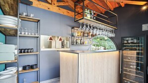 Uma área de bar com prateleiras de copos, garrafas e um climatizador de vinhos.