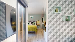 Quarto moderno com cama, mesa de cabeceira e parede com padrões geométricos.