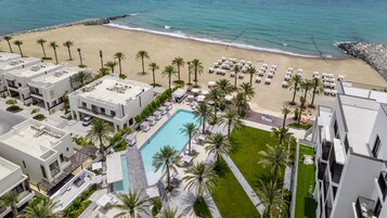 Resort com piscina, praia e palmeiras.