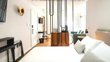 Quarto de hotel moderno com uma cama grande, uma escrivaninha e uma kitchenette.