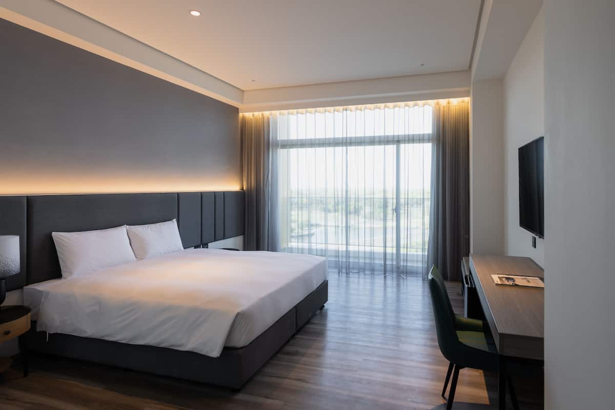 Quarto de hotel moderno com uma cama grande, uma mesa e uma televisão.