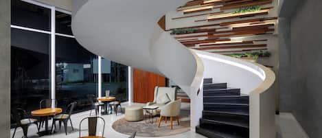 Interior moderno com escada em espiral, área de estar e vista através de grandes janelas.