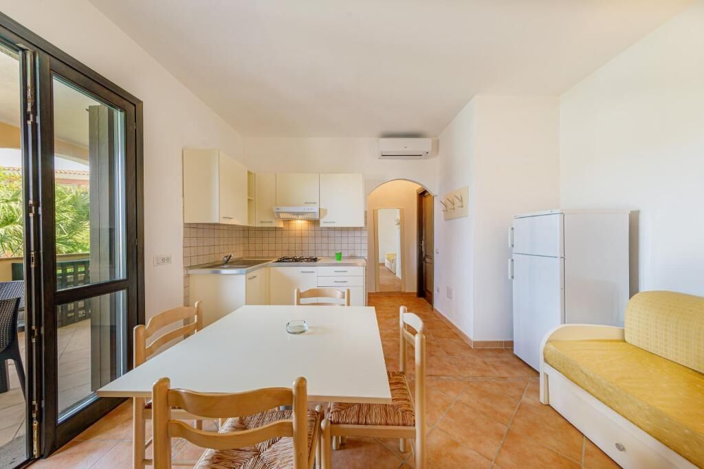 Uma cozinha compacta com espaço para refeições, um sofá e uma porta de vidro deslizante que dá para uma área externa.