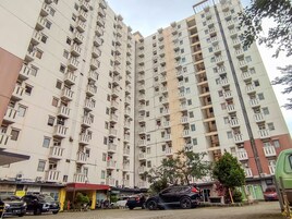 Um edifício residencial com vários andares, varandas, área de estacionamento e uma pequena loja no andar térreo.
