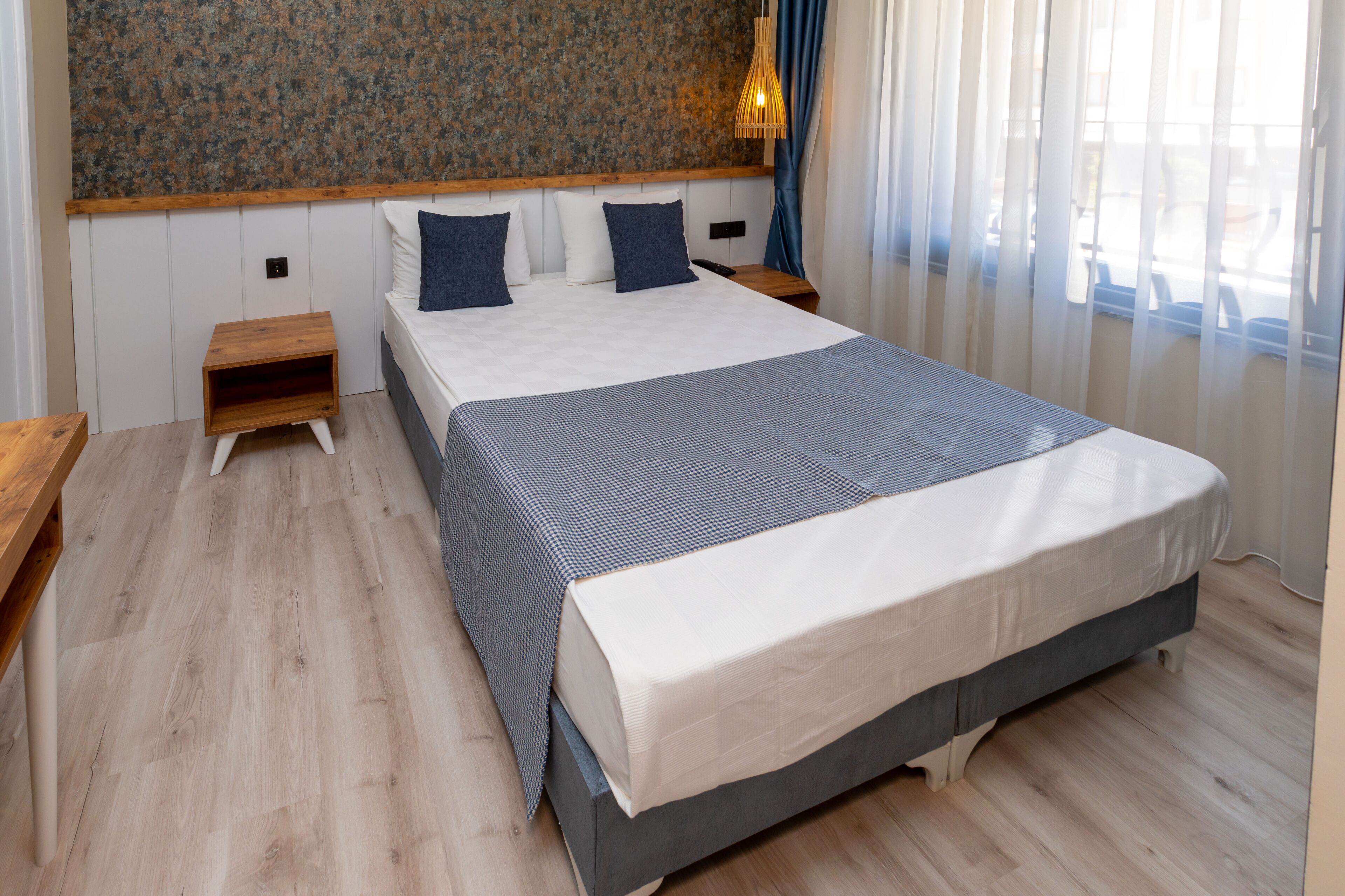 Quarto com uma cama grande, mesas de cabeceira de madeira e cabeceira de madeira, além de uma parede com padrão.