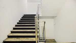 Escada com degraus pretos e corrimão cromado.
