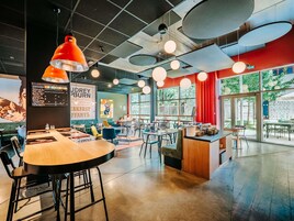 Um restaurante moderno com mesas redondas, luminárias pendentes e grandes janelas.